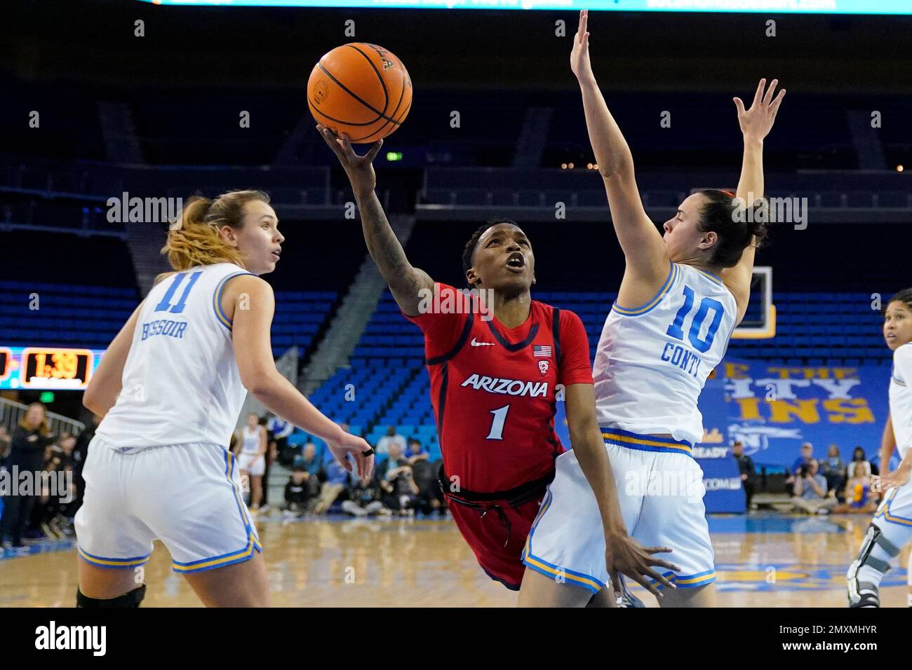 Arizona guard Shaina Pellington, center, shoots as UCLA forward Emily ...