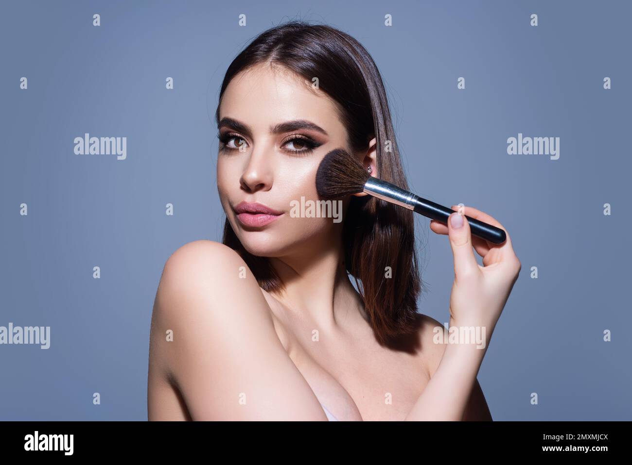 Young woman applies powder on the face using makeup brush. Beautiful ...