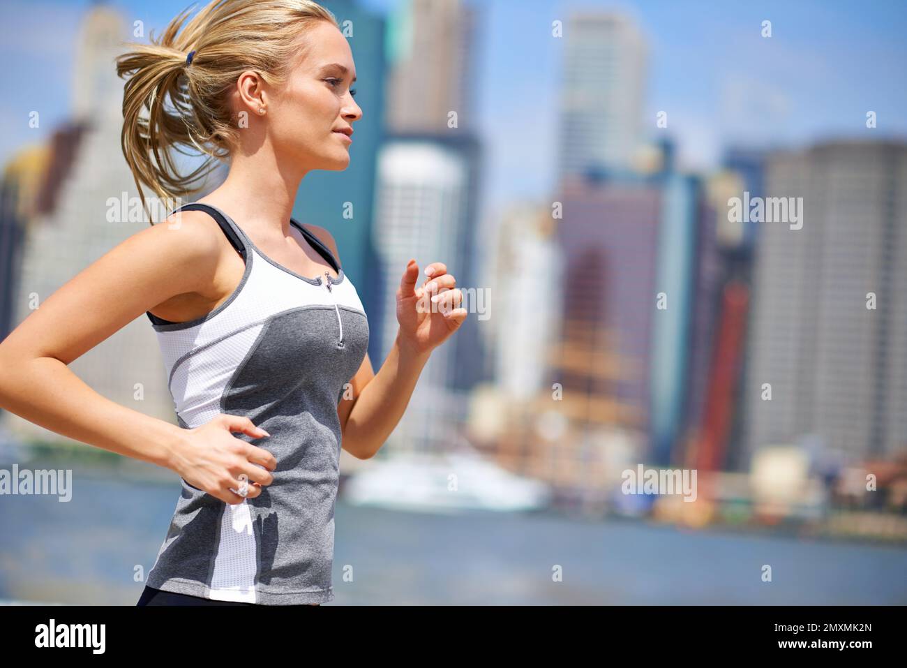 The urban runner. an attractive blonde woman jogging in an urban ...