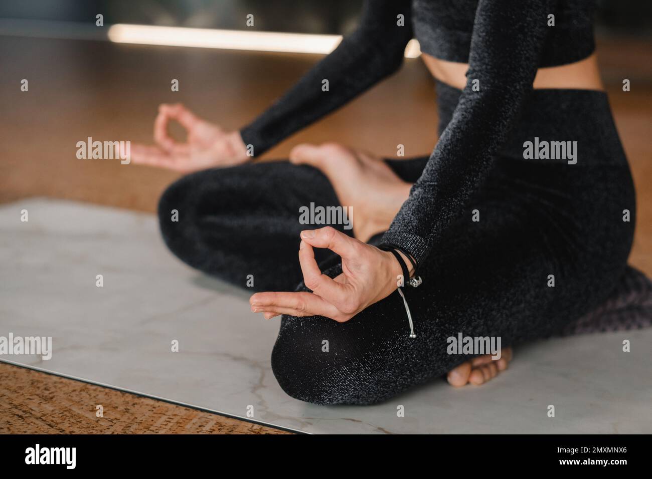 Close-up of the legs and arms of a woman in a black tracksuit sitting ...
