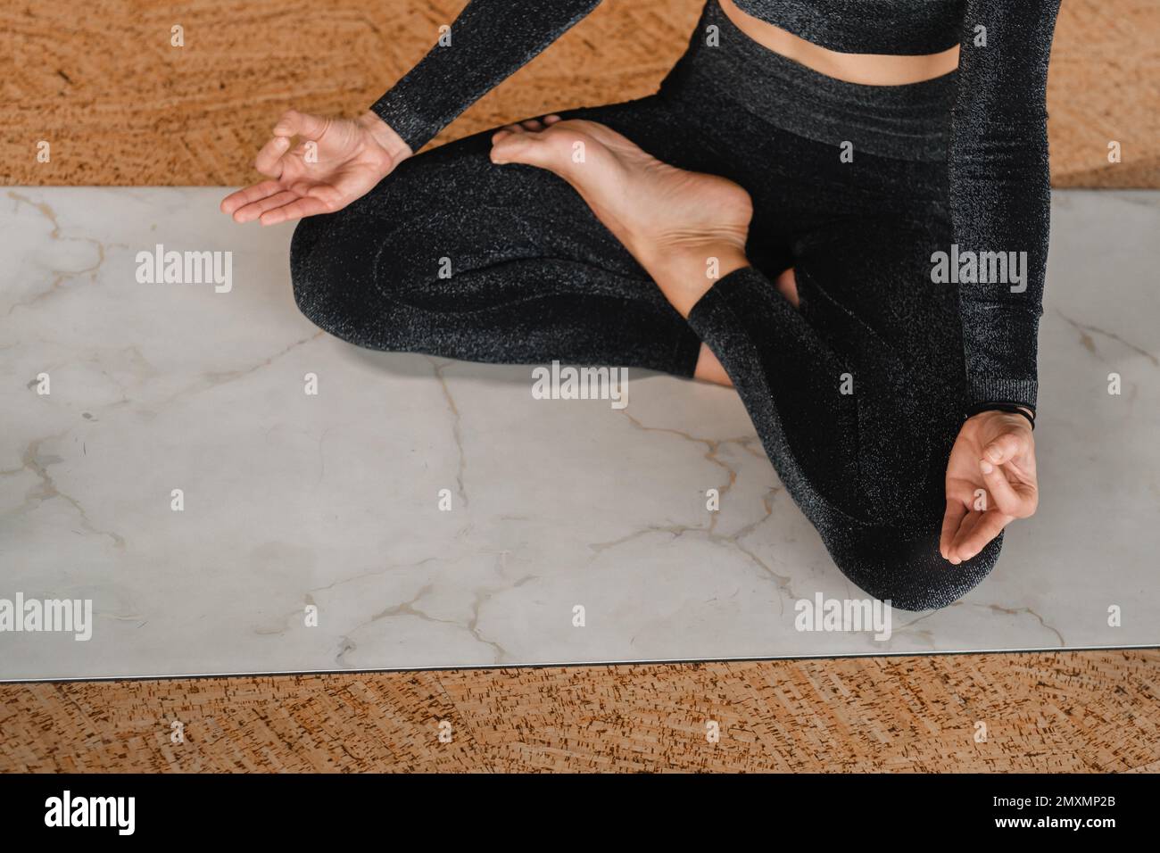 Close-up of the legs and arms of a woman in a black tracksuit sitting ...