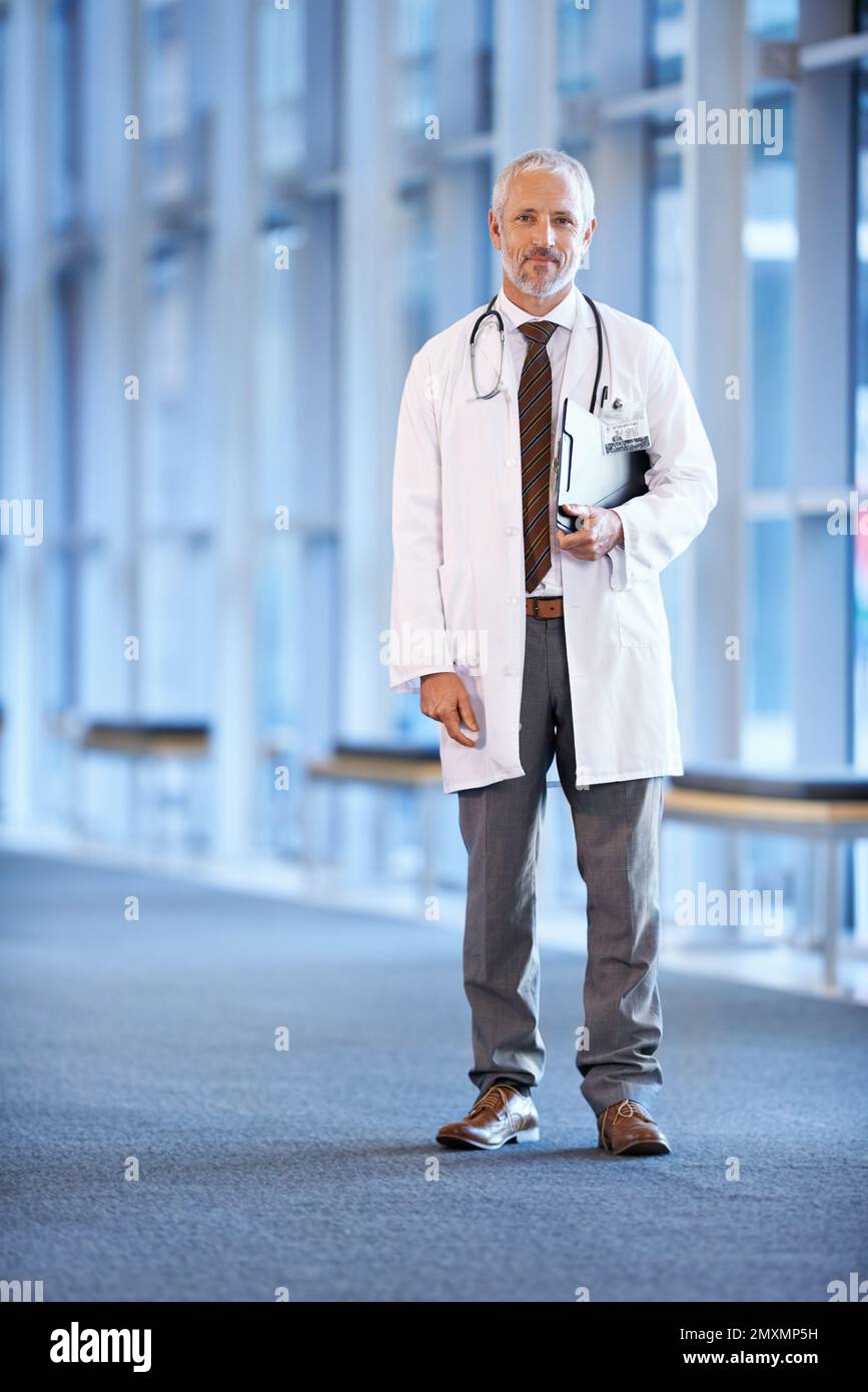 Just doing my rounds. Portrait of a mature doctor holding a patient ...