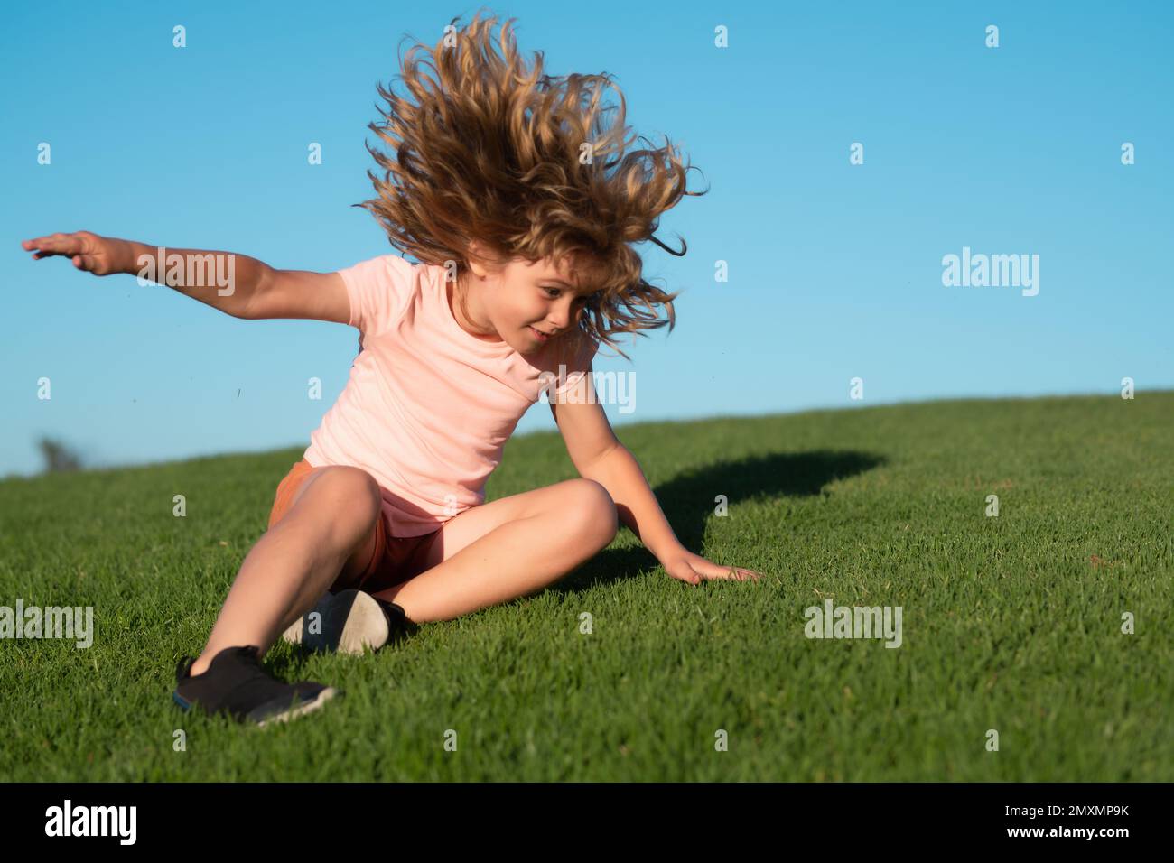 Kid falling down on the grass. Moment of the fall down. Little child ...