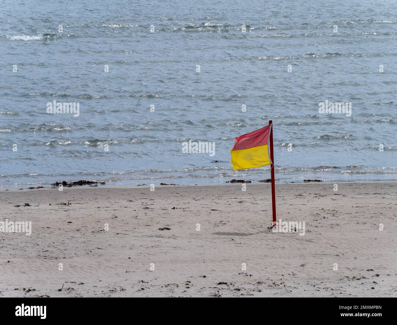 Red and yellow flag allowing swimming on the sandy seashore. Public ...
