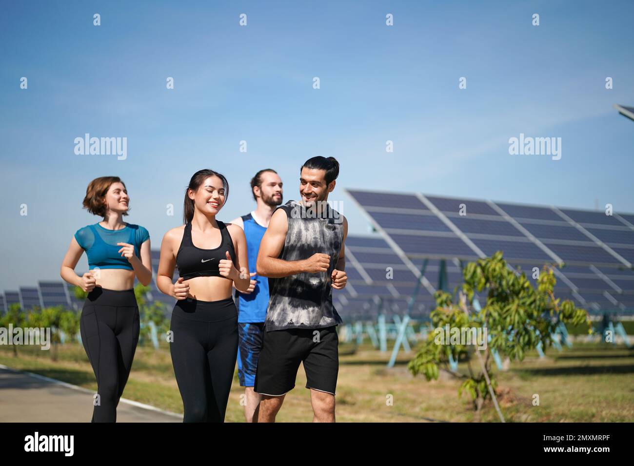 Active lifestyle young runner man running by solar panels farm outdoors ...