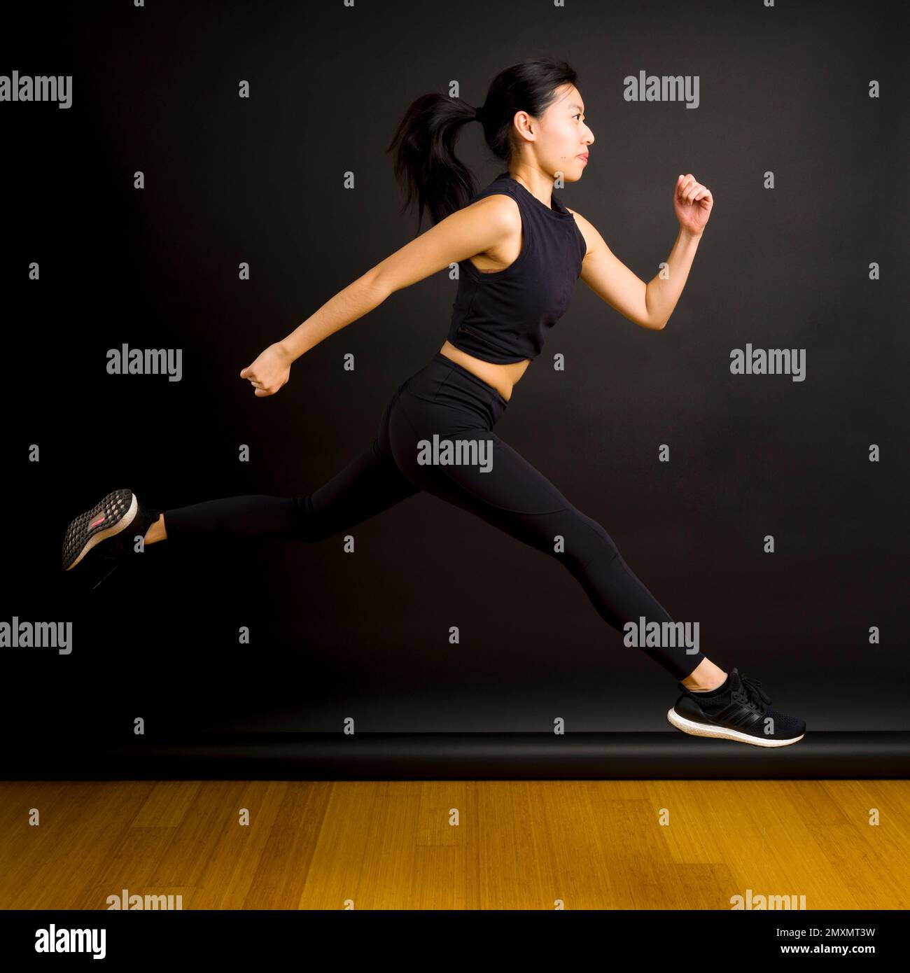 Beautiful Young Asian Runner Woman Taking a Long Stride in the Studio ...