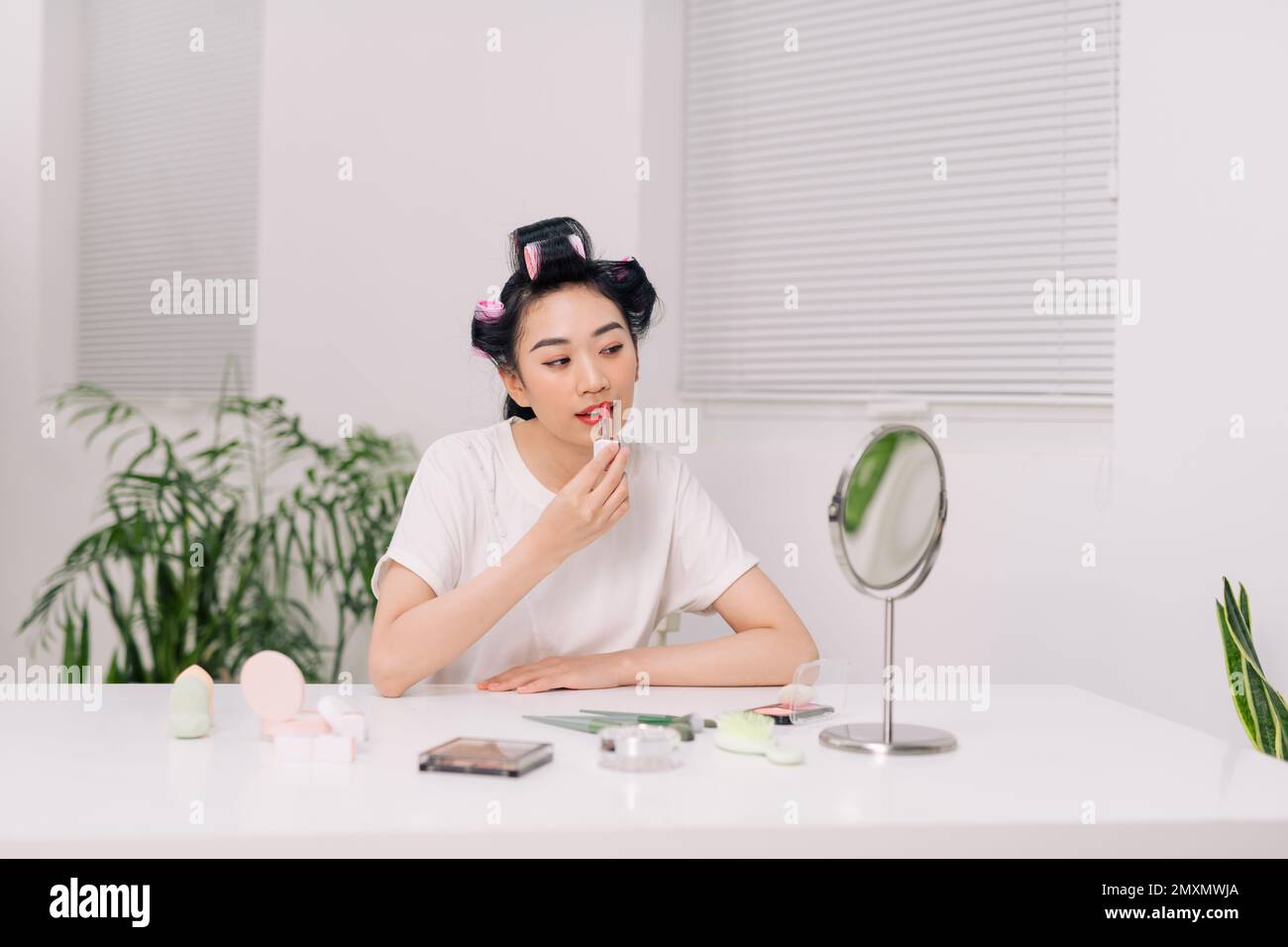 Young woman doing her makeup in the mirror Stock Photo - Alamy