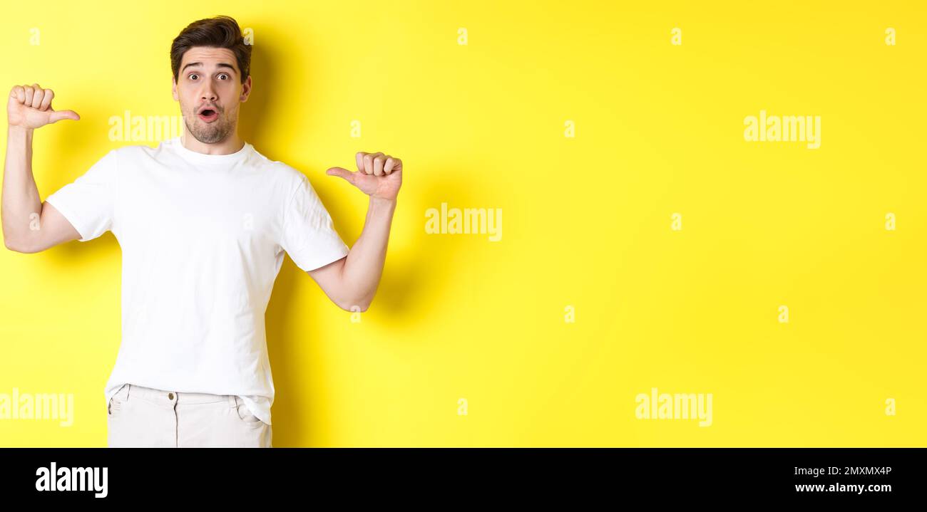 Surprised handsome guy pointing at himself, looking amazed, standing ...