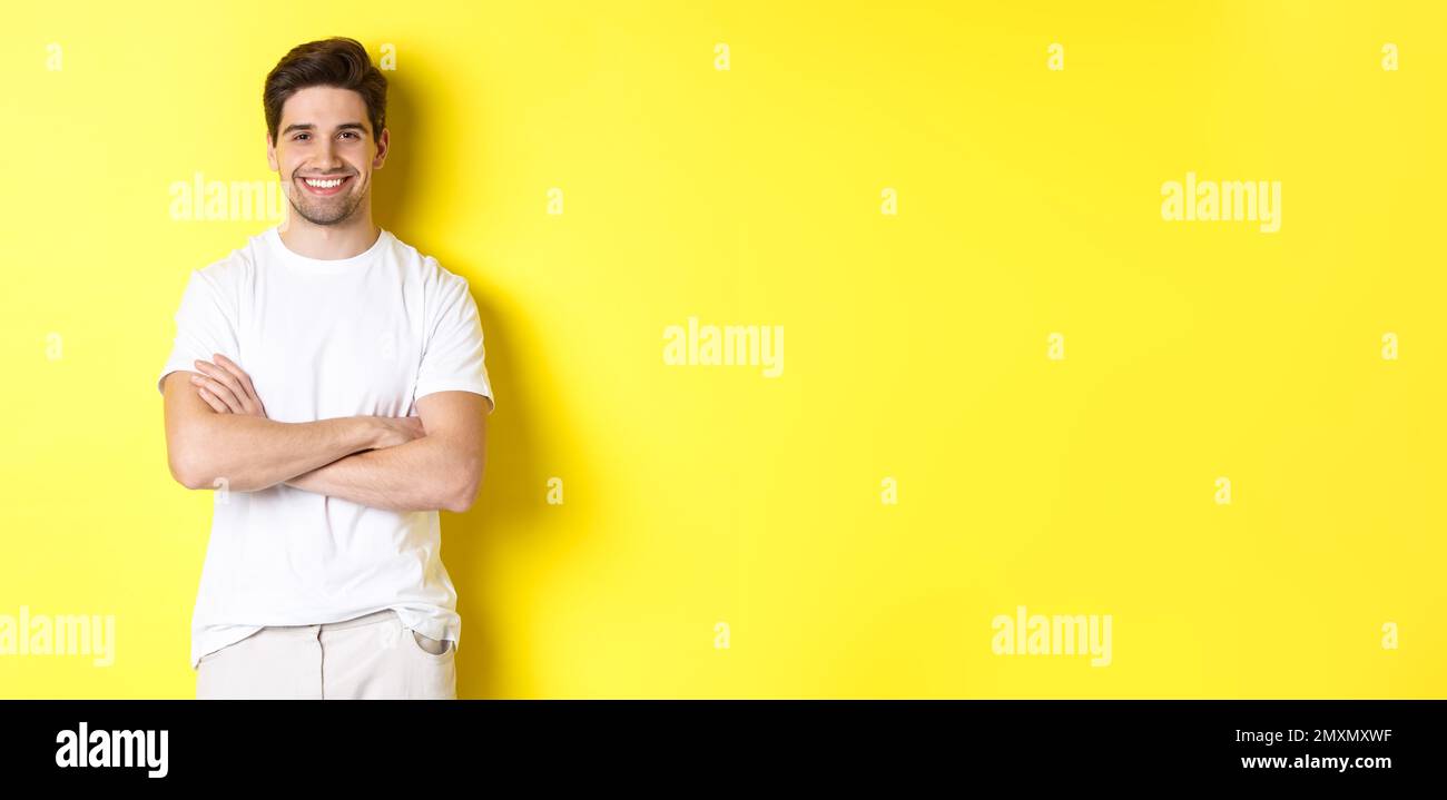 Image of confident caucasian man smiling pleased, holding hands crossed ...