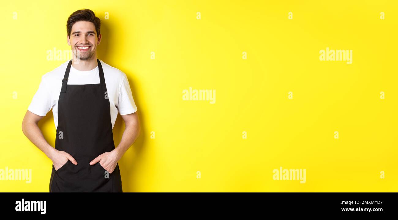 Happy barista in black apron looking at camera. Coffee shop owner ...
