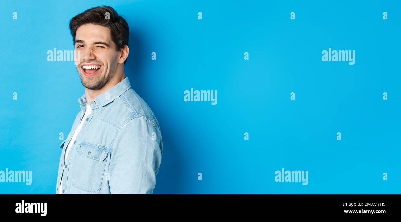 Happy and confident man turn head at camera, winking and smiling ...