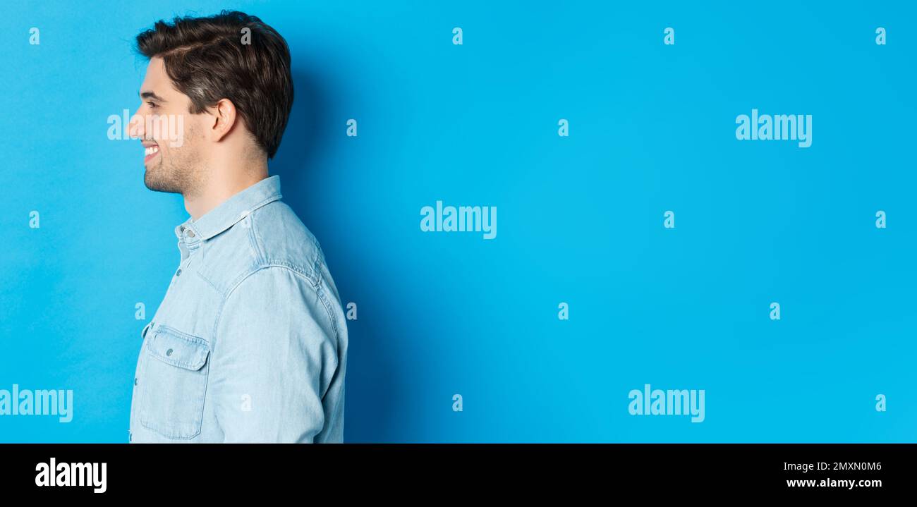 Profile of handsome young man looking left, smiling happy, standing ...
