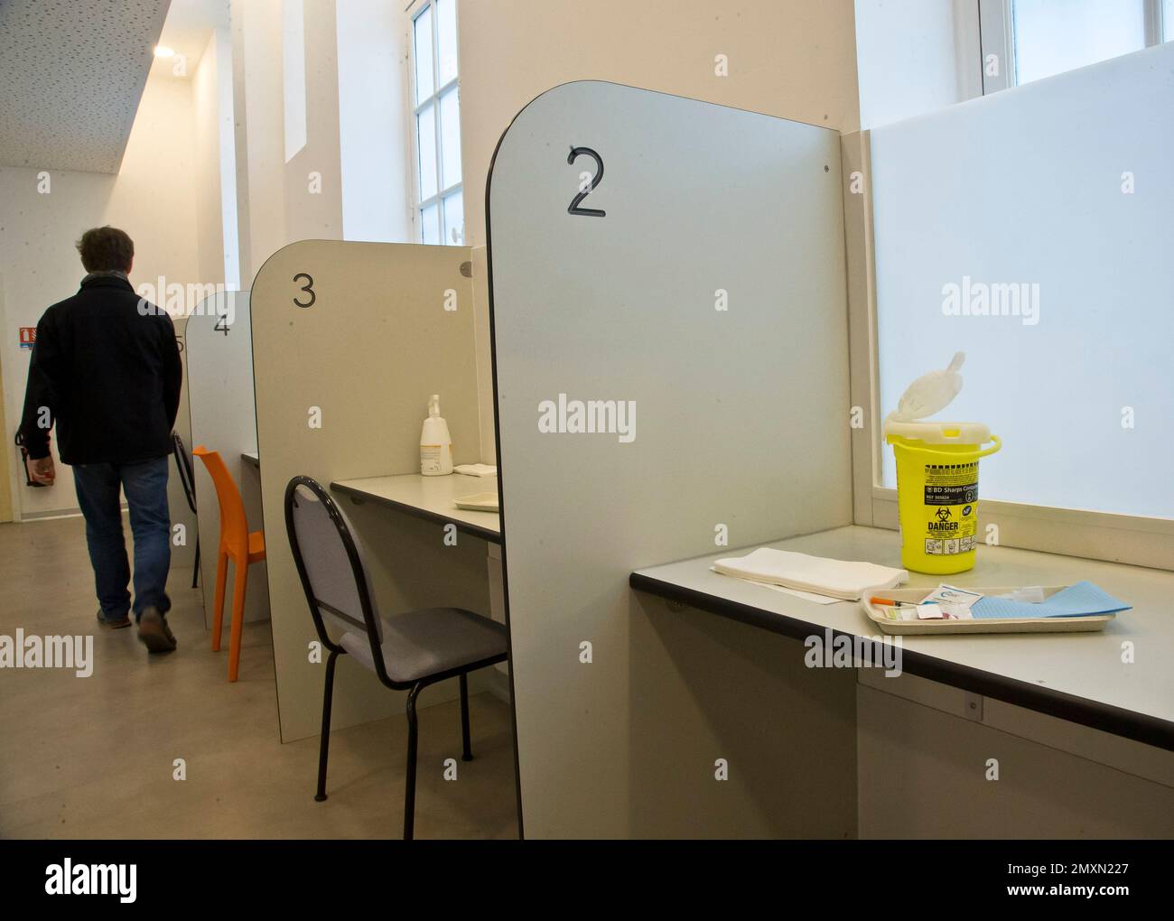 An aid worker walks along the cubicles in first safe- injection room ...