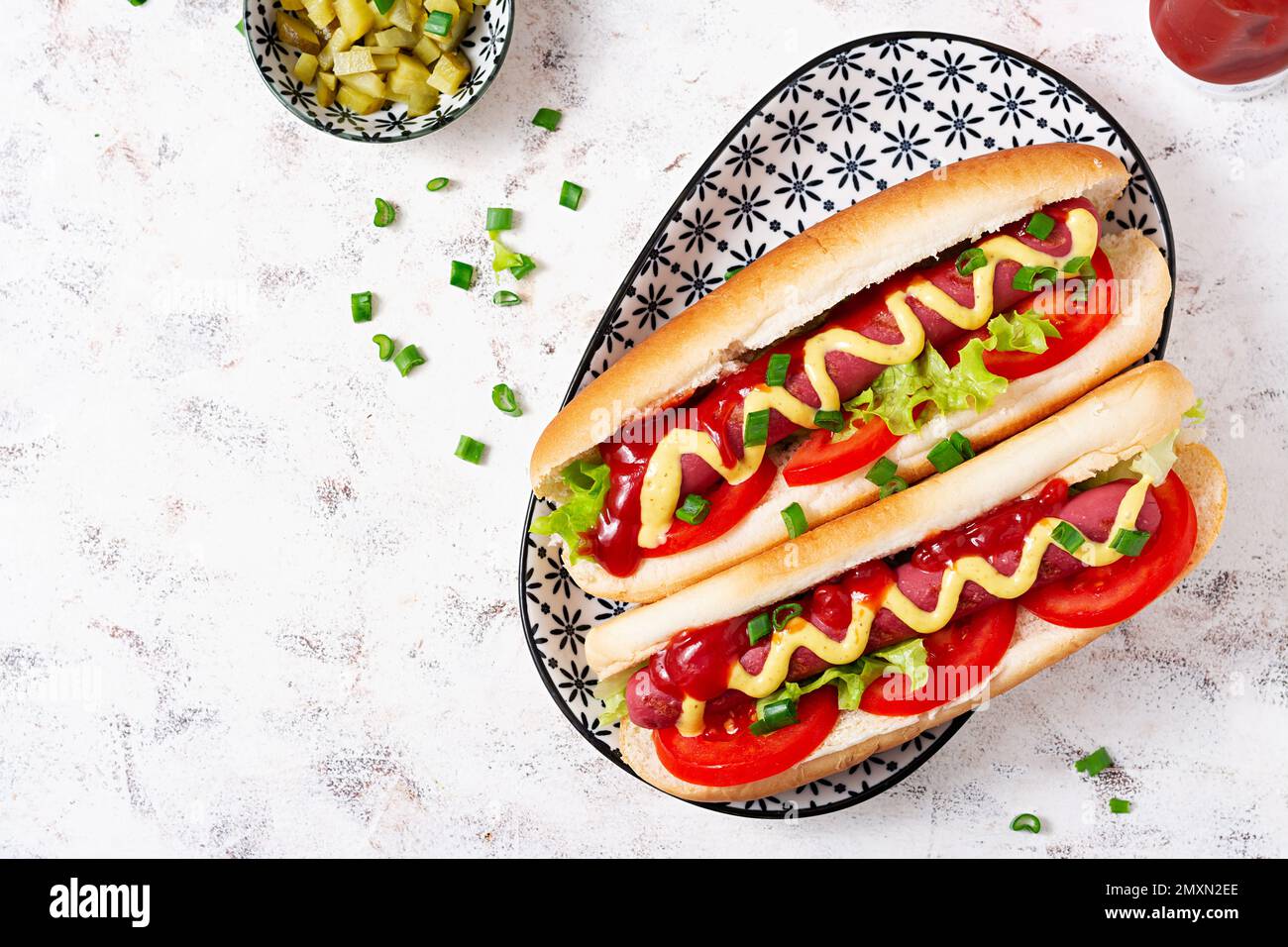 Hot dog with grilled sausage, tomato and lettuce on light background ...