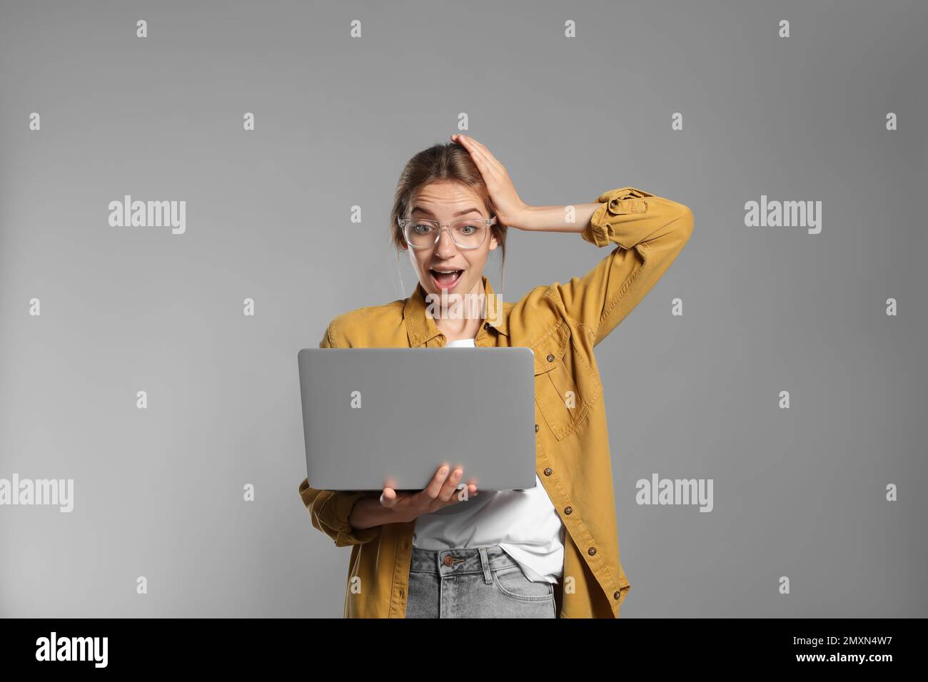 Portrait of emotional woman with modern laptop on grey background Stock ...