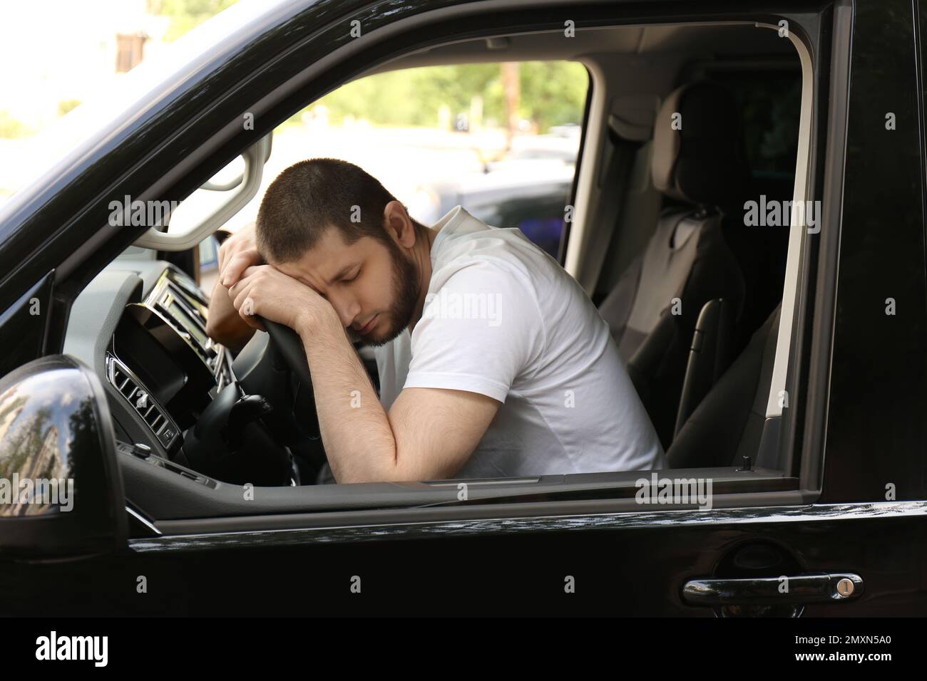 Tired man sleeping on steering wheel in his car Stock Photo - Alamy