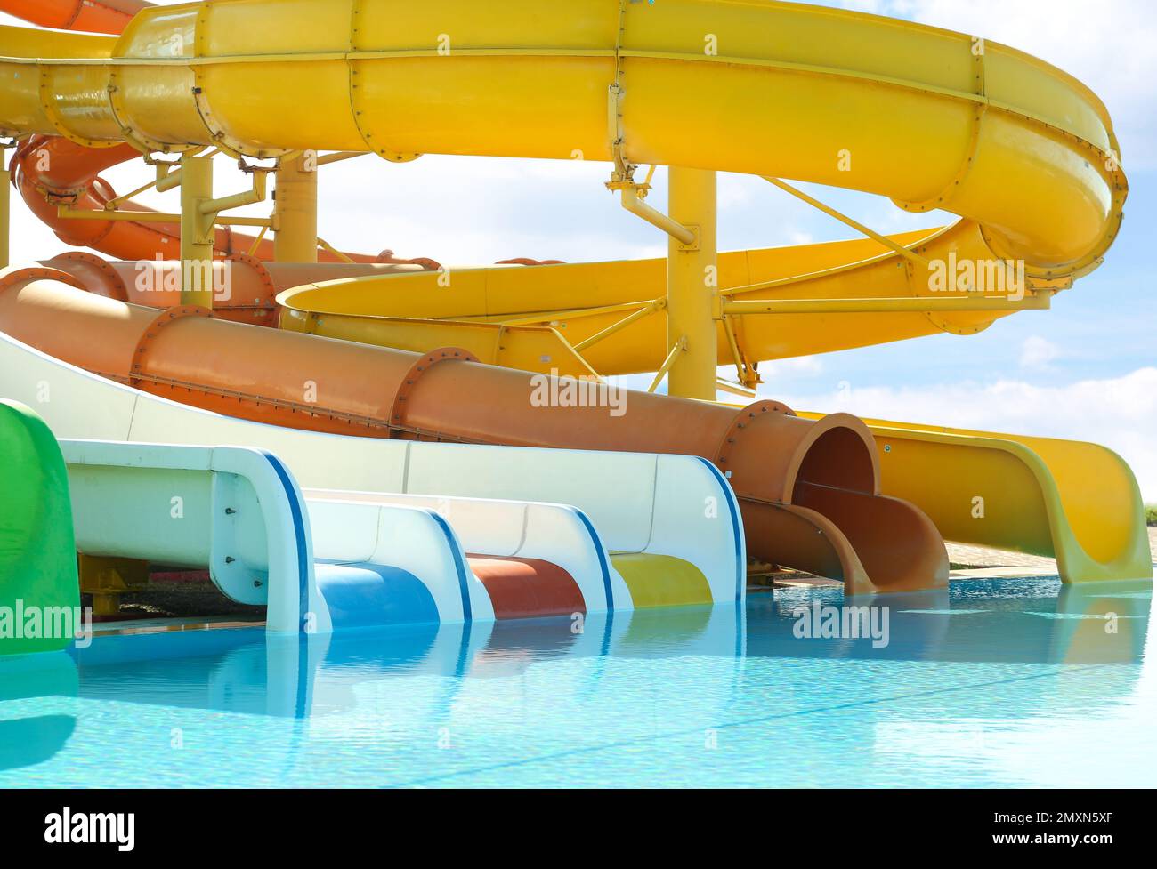 Different colorful slides and swimming pool in water park on sunny day ...