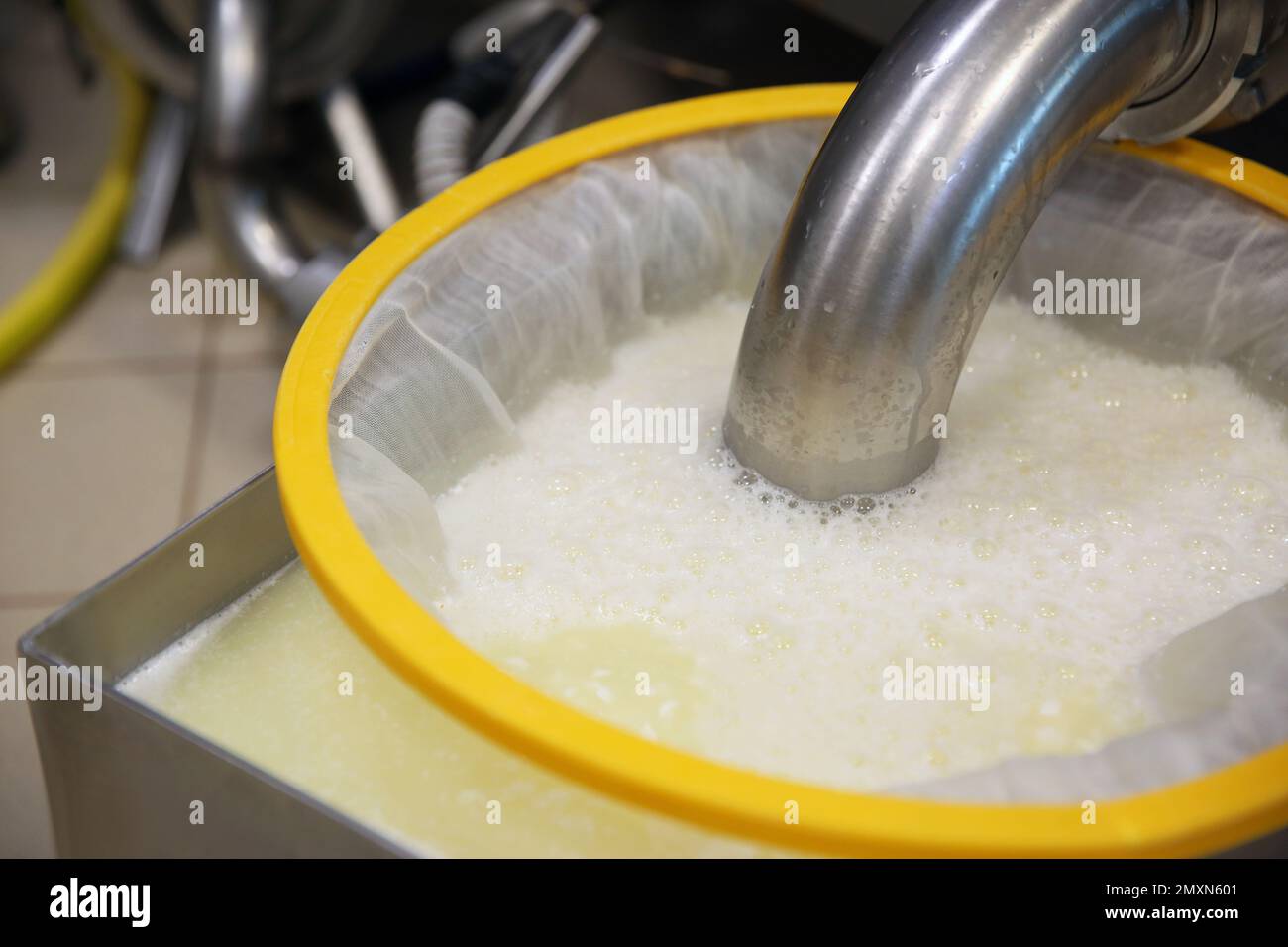 Draining whey from tank into sieve at cheese factory, closeup Stock ...