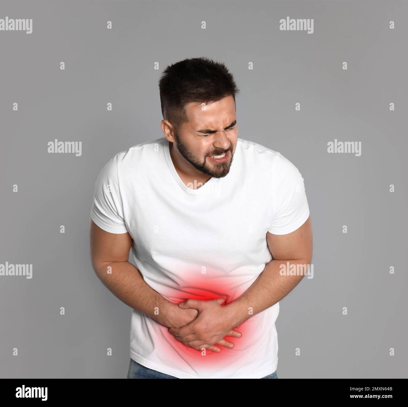 Man suffering from abdominal pain on grey background Stock Photo - Alamy