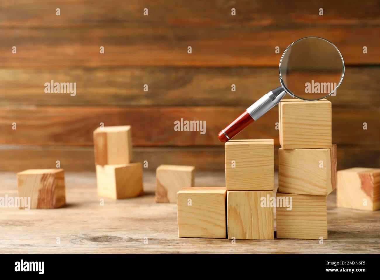 Magnifier glass and stairs made with cubes on wooden background, space ...