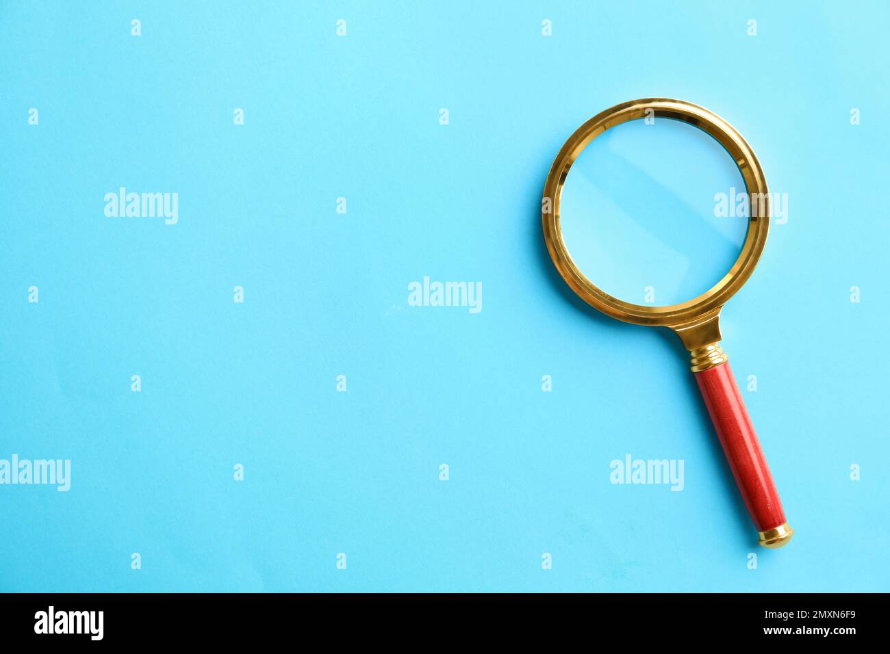Top view of magnifier glass on light blue background, space for text ...