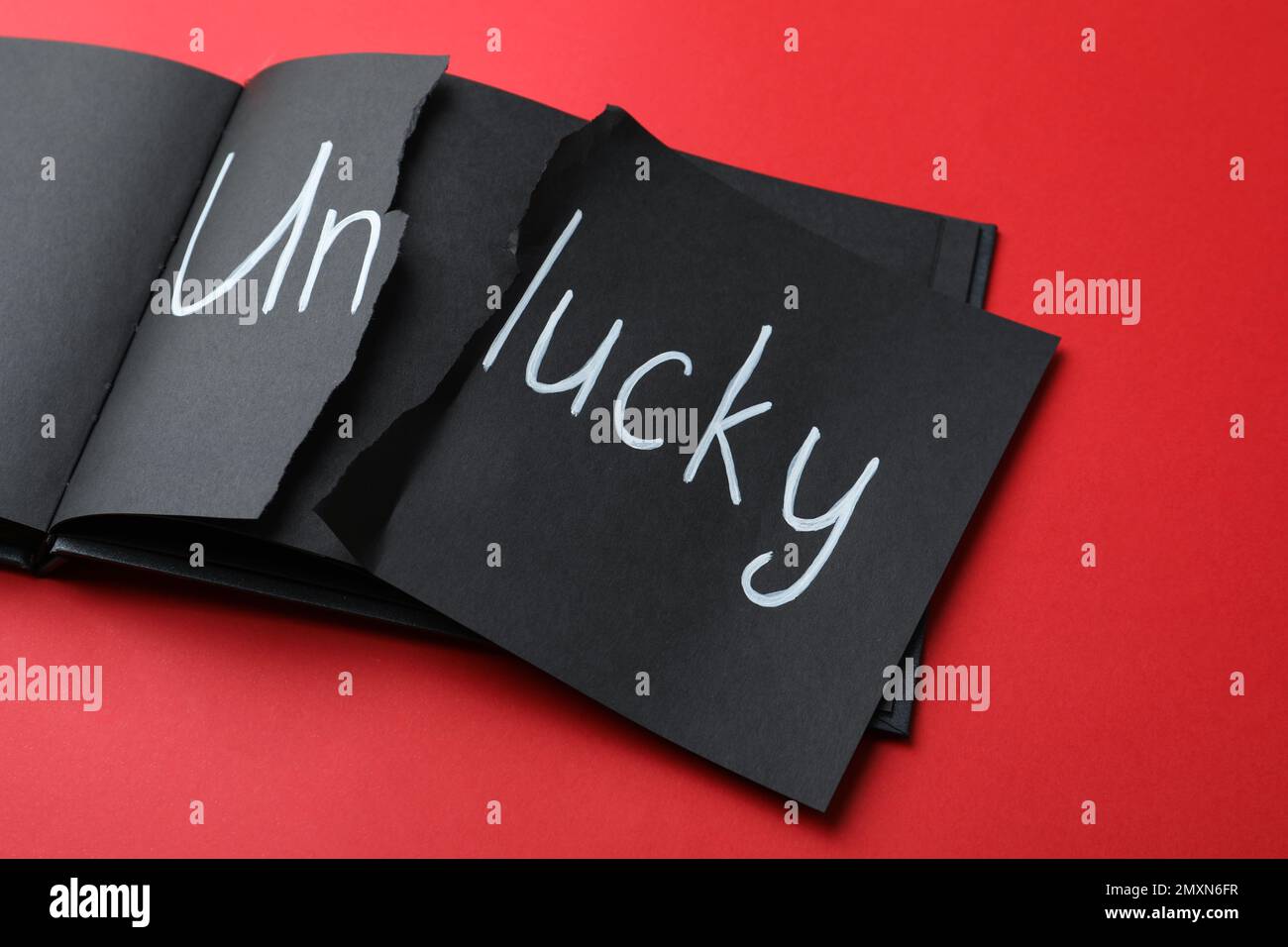 Torn word UNLUCKY written in notebook on red background Stock Photo - Alamy