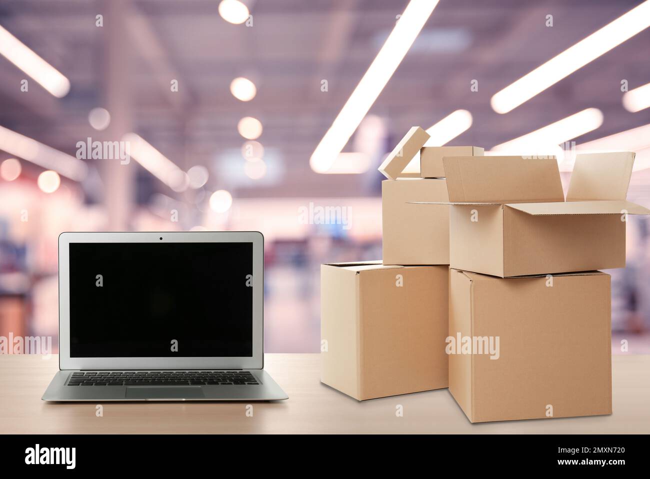 Online selling. Laptop and parcels on table in store Stock Photo - Alamy
