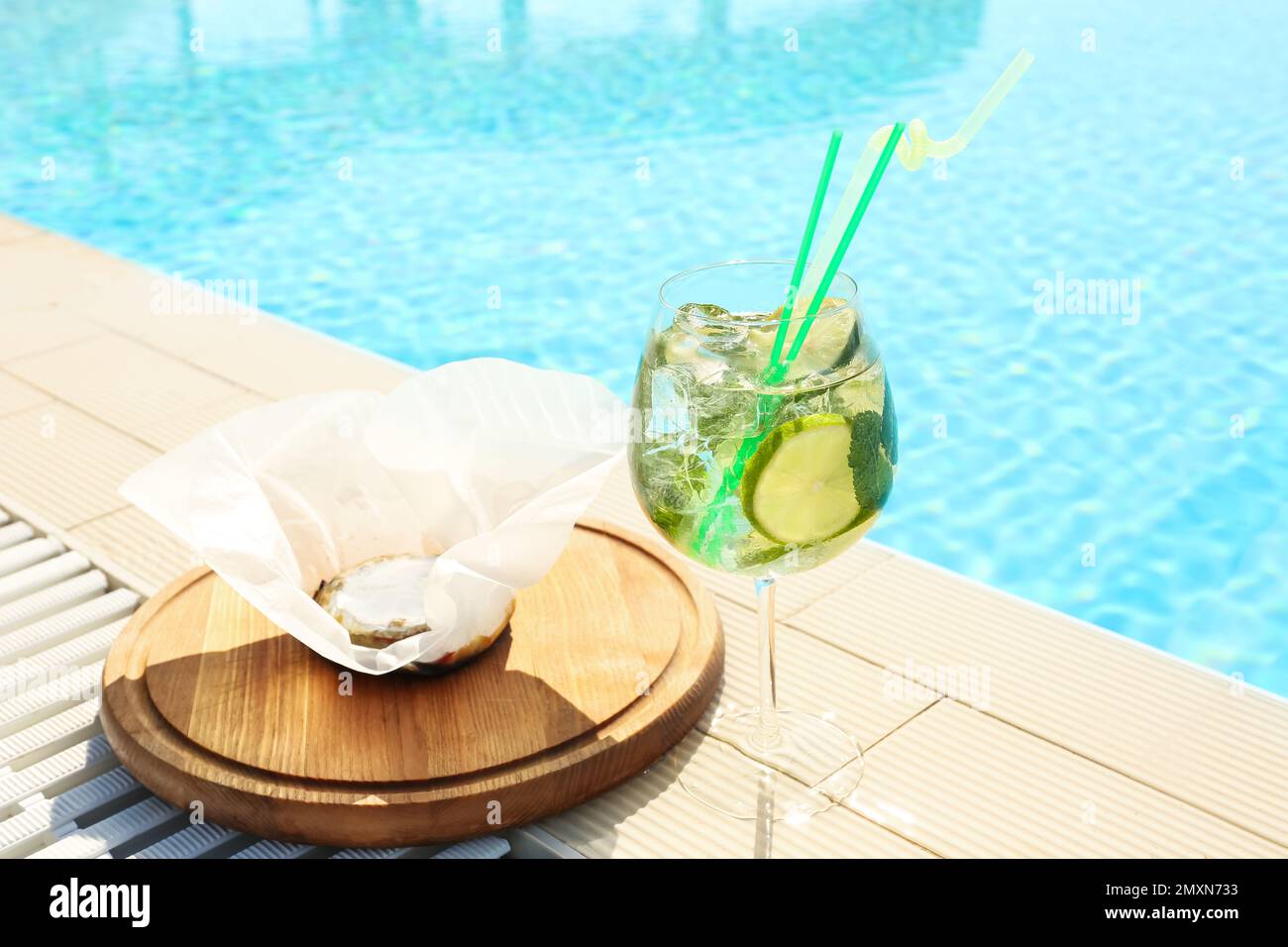 Glass of delicious mojito and brie cheese near swimming pool ...