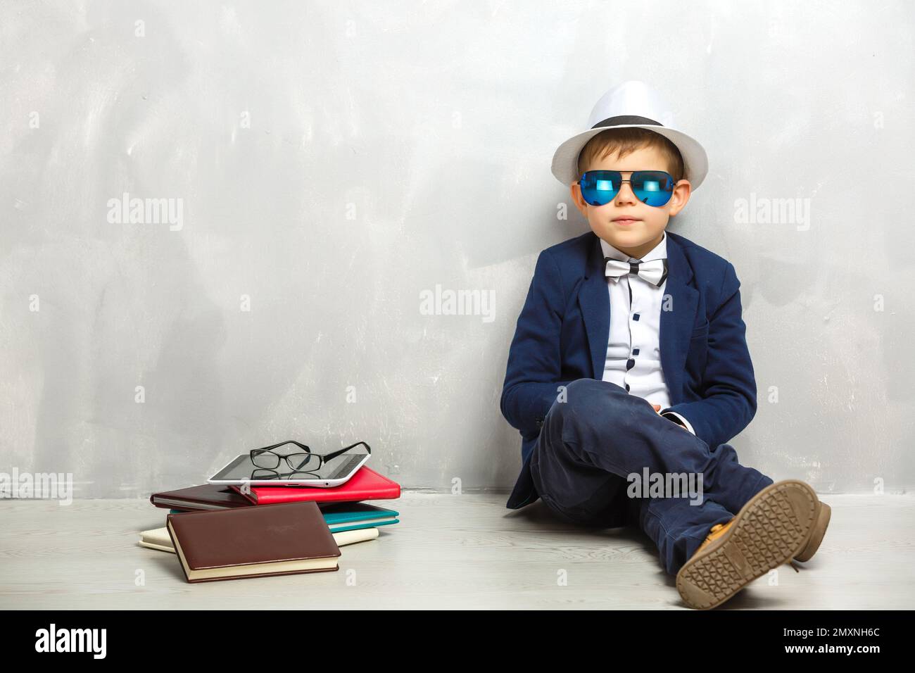 Elementary school student carrying notebooks over a gray background ...