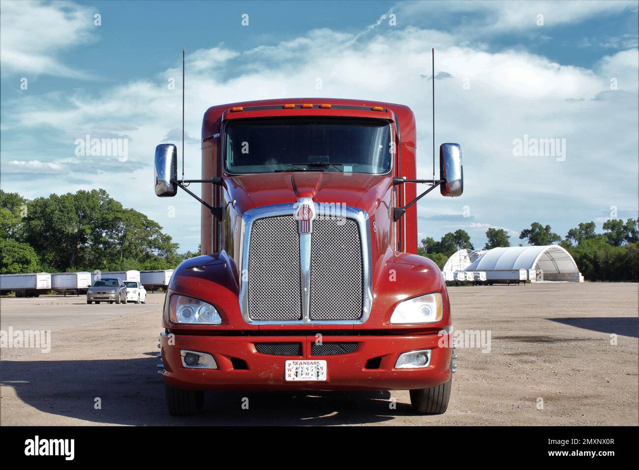Red Kenworth Truck in a parking lot with blue sky and clouds with tree ...