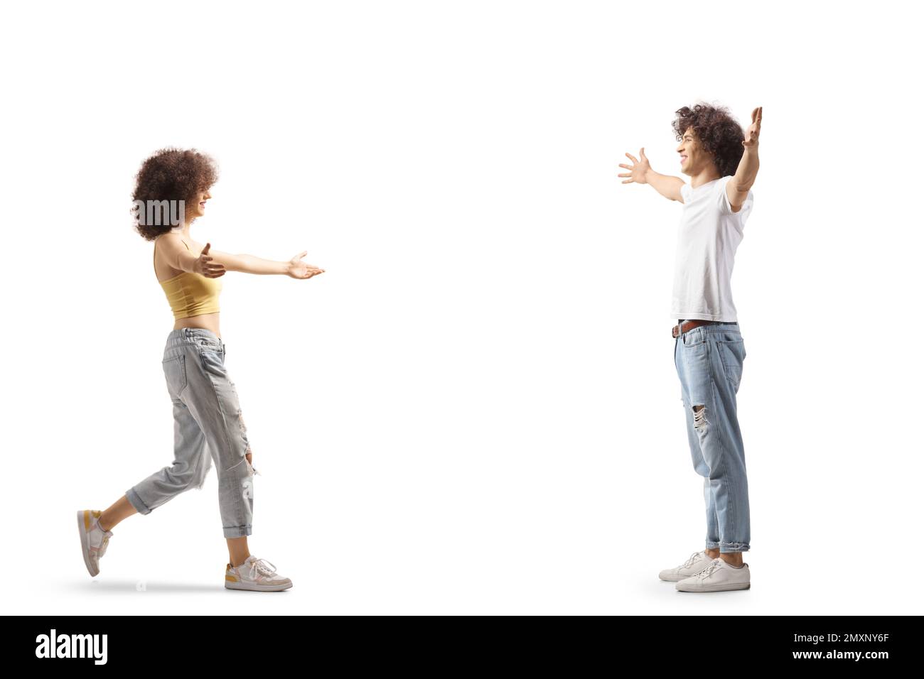 Full length profile shot of a young woman walking to hug a young casual ...