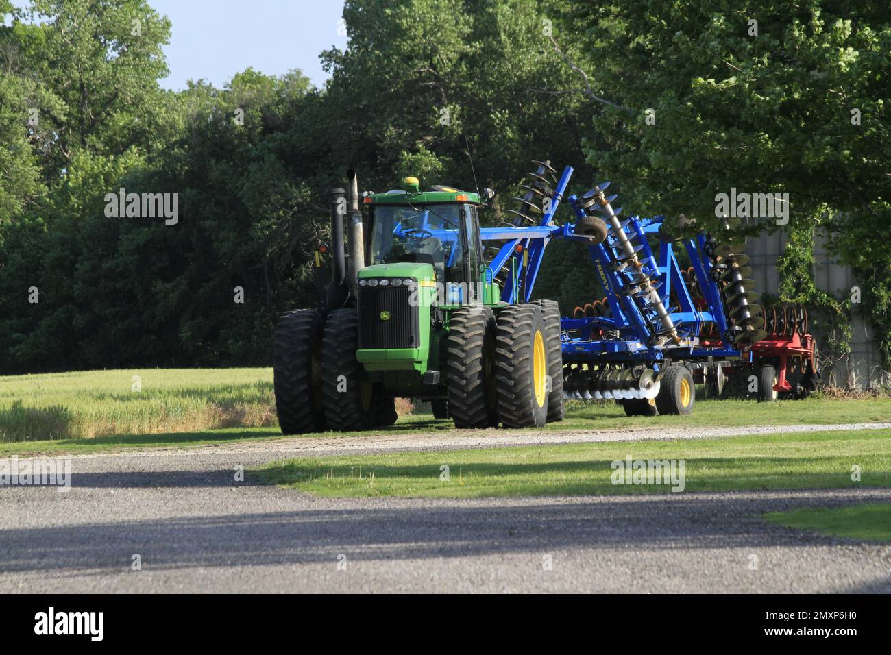 A John Deere farm tractor in a farm field with an Implement on the back ...