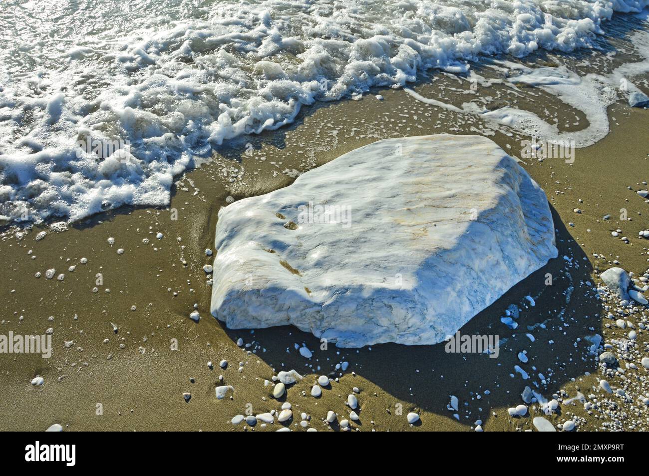 A large smooth block of white marble in the sand on the coast Stock ...