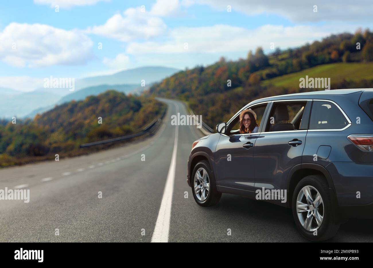 Road trip. Young beautiful woman in car on asphalt highway, space for ...