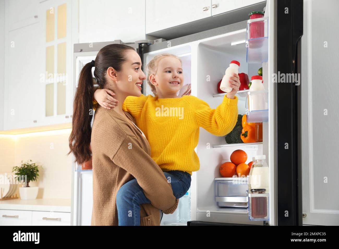 Young mother and daughter near open refrigerator in kitchen Stock Photo ...