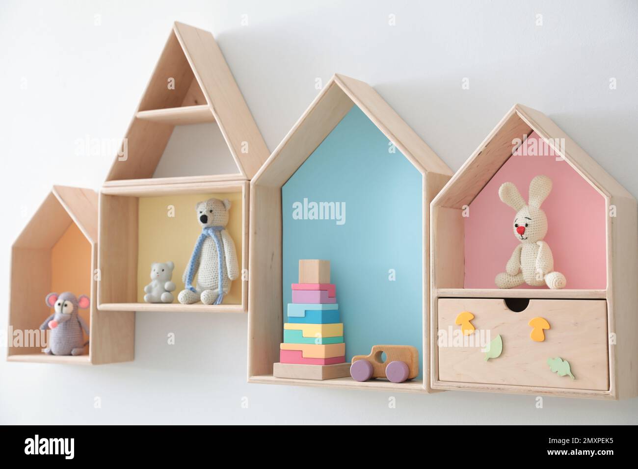 Different house shaped shelves with toys on white wall. Interior design ...