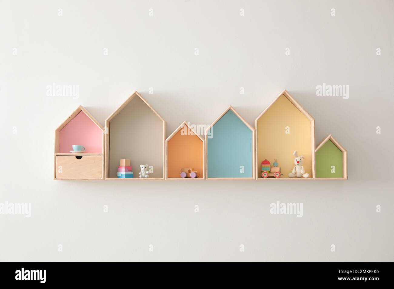 Different house shaped shelves with toys on white wall. Interior design ...