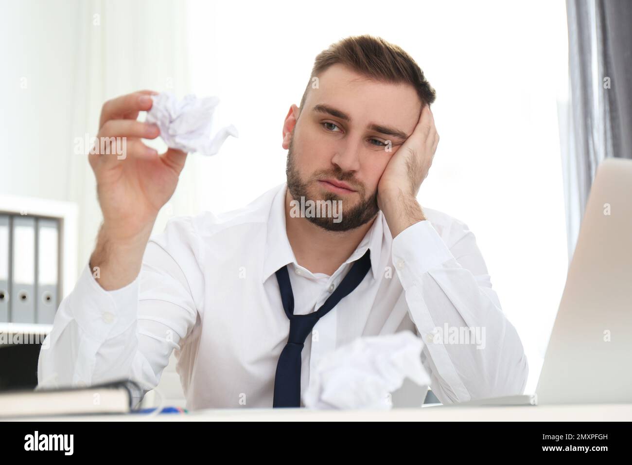 Lazy young man with crumpled paper at messy table in office Stock Photo ...