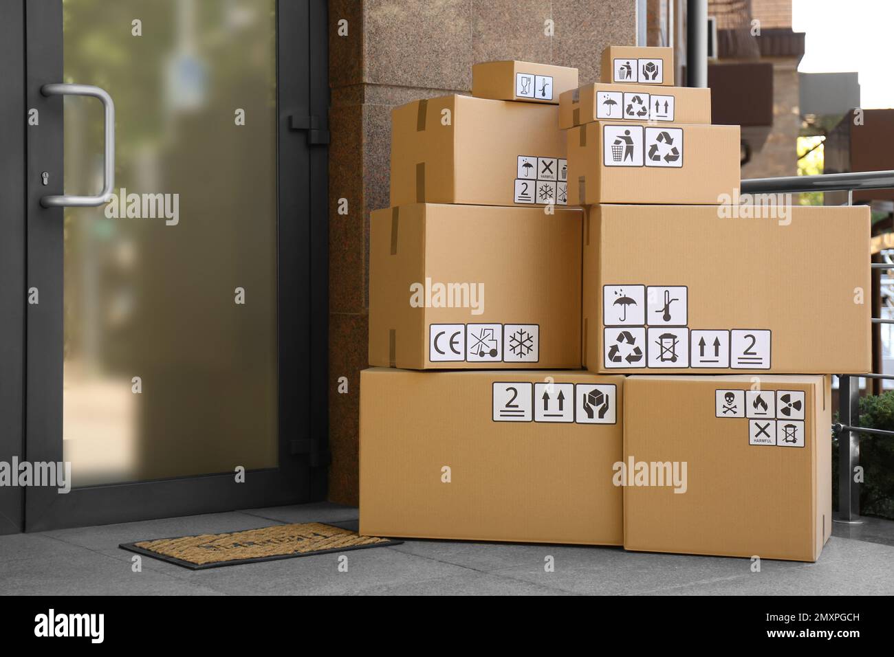 Cardboard boxes with different packaging symbols on porch near entrance ...