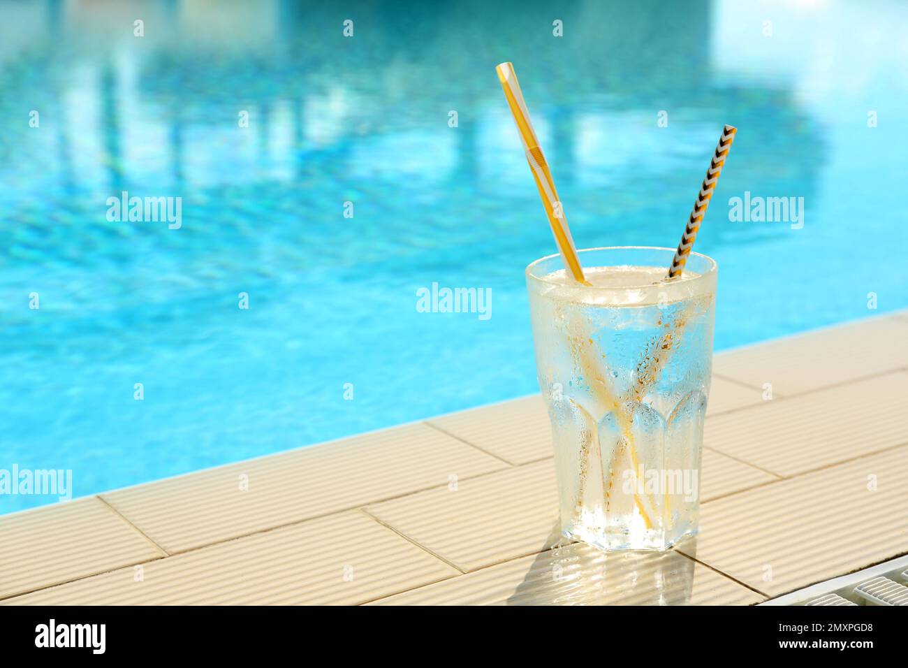 Glass of refreshing drink near swimming pool. Space for text Stock ...