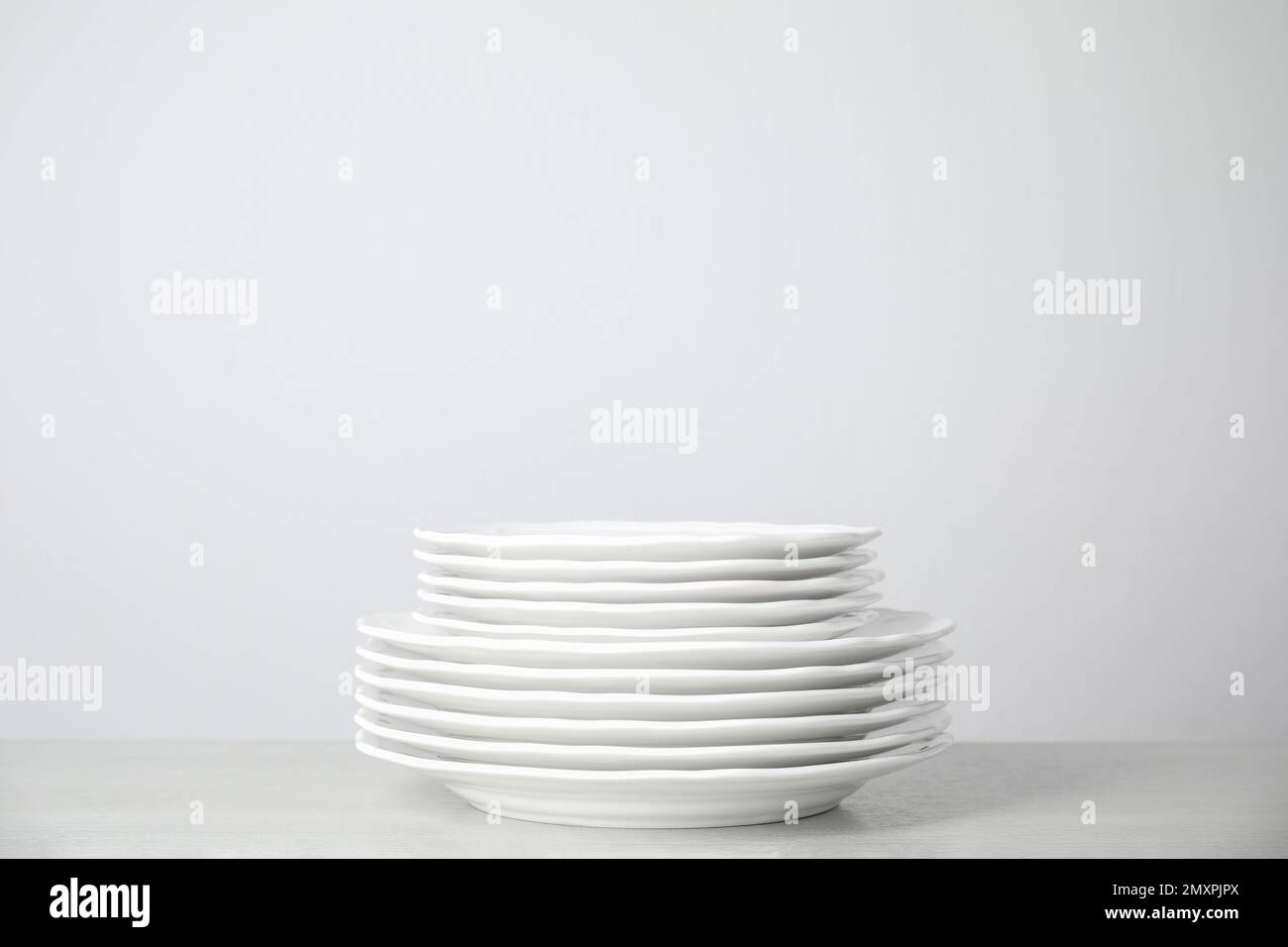 Stack of clean plates on table against white background. Space for text ...