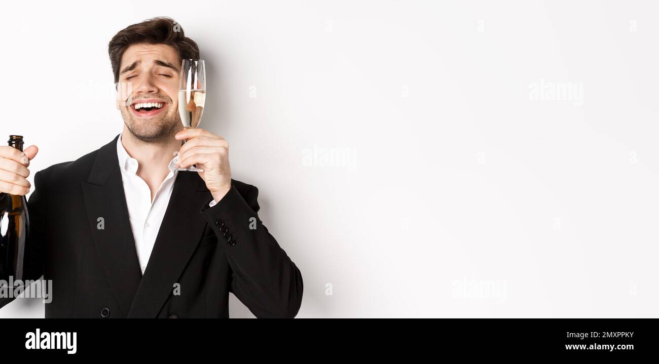 Close-up of handsome drunk guy in suit, holding glass of champagne and ...