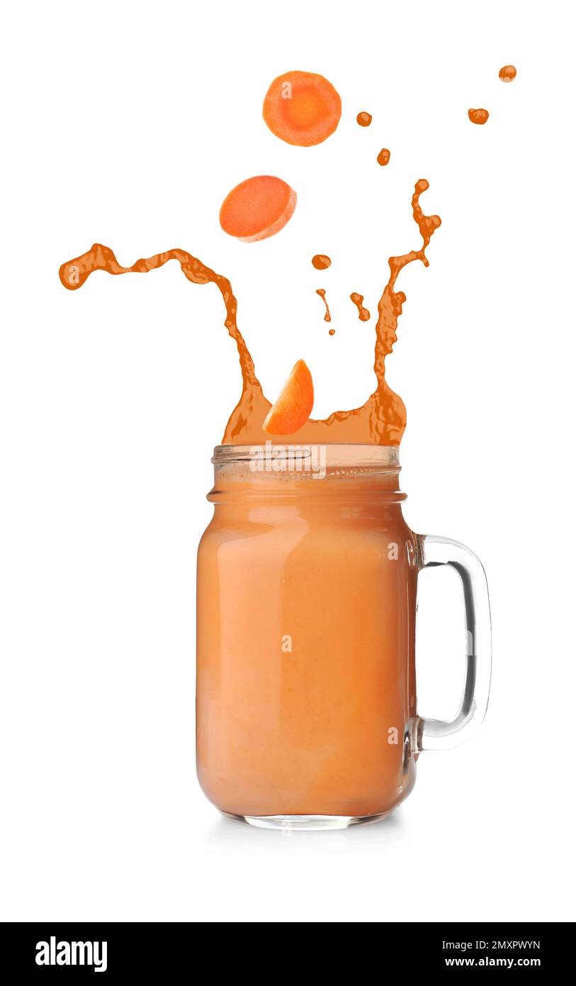 Carrot slices falling into mason jar of fresh juice with splashes on ...