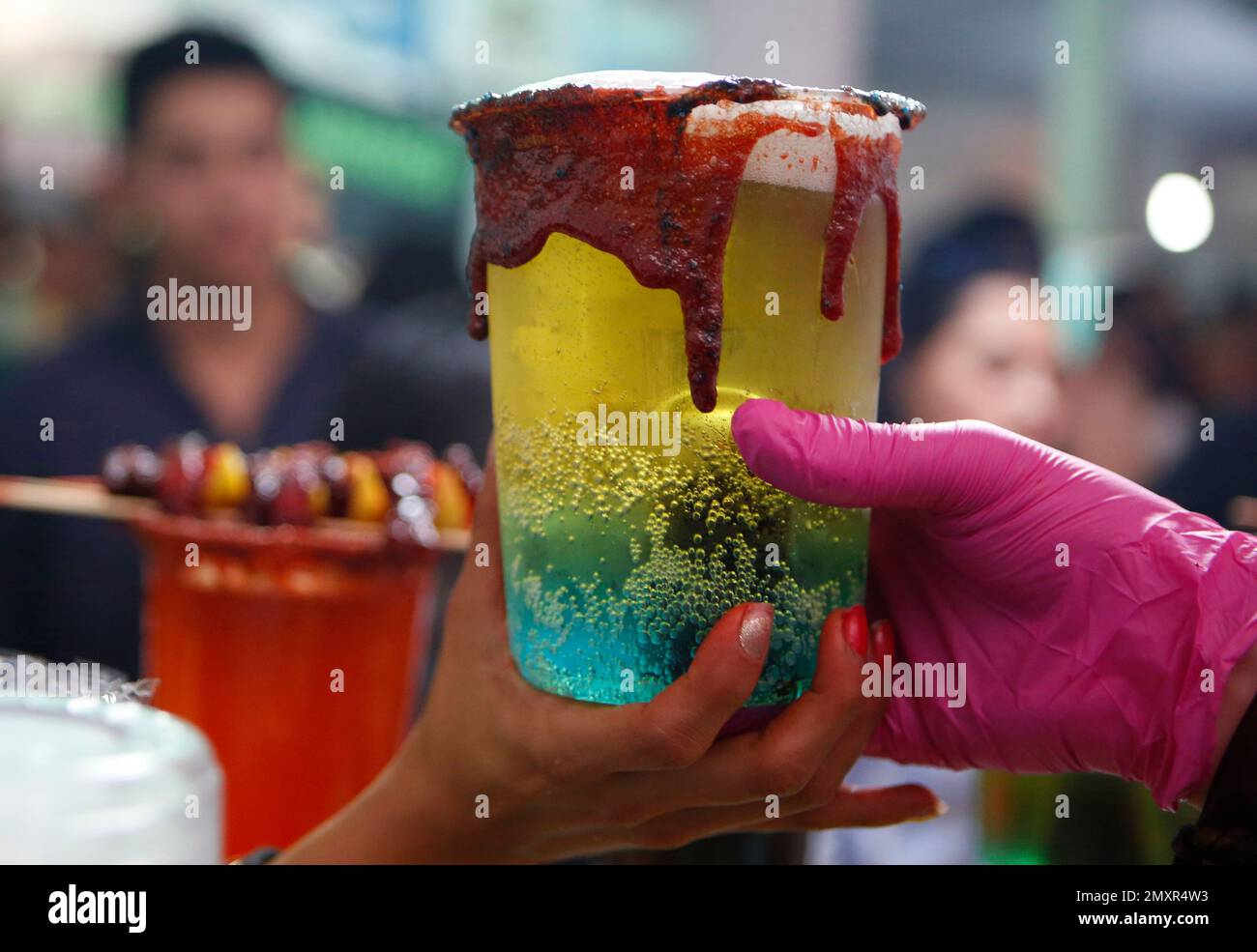 A michelada maker hands a finished concoction to a customer at the ...