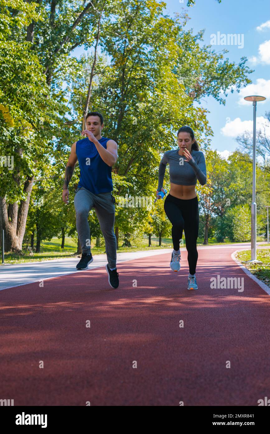 Two adult fitness models running in the park Stock Photo - Alamy