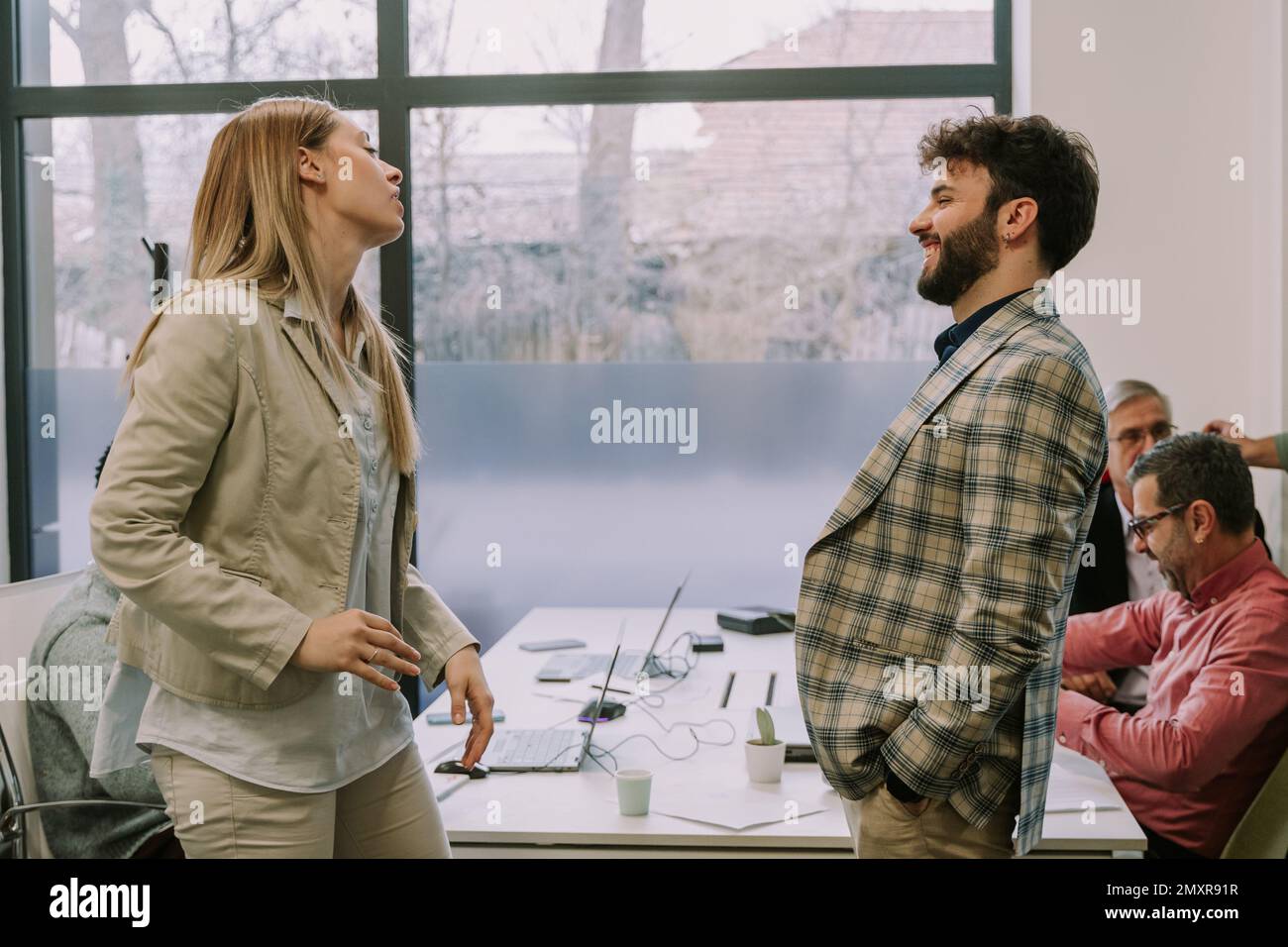 Two colleagues talking while the rest of the team works in the ...