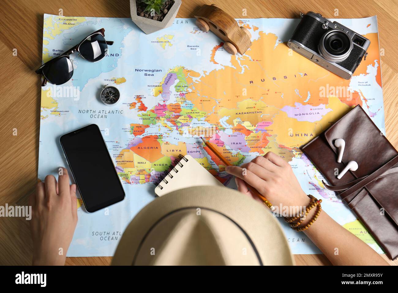 Woman with notebook and world map planning trip at wooden table, top ...