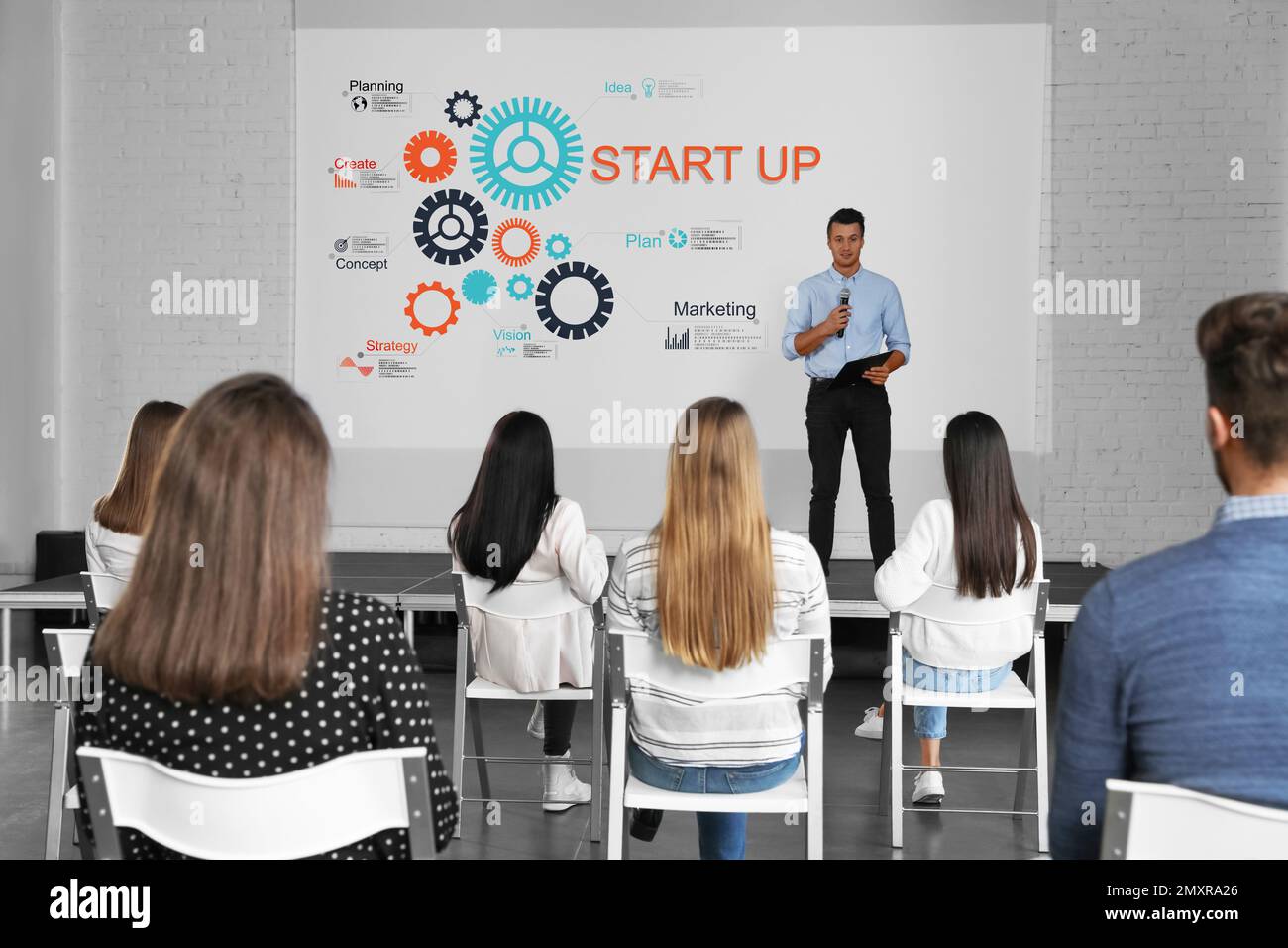 Business trainer giving lecture in conference room with projection ...