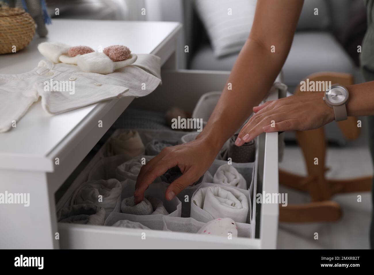 Woman taking baby clothes from chest of drawers, closeup Stock Photo ...