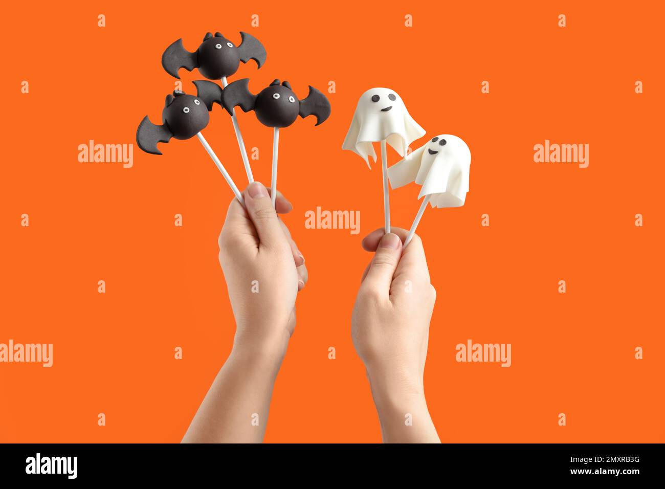 Woman with delicious ghost and bat shaped cake pops on orange ...